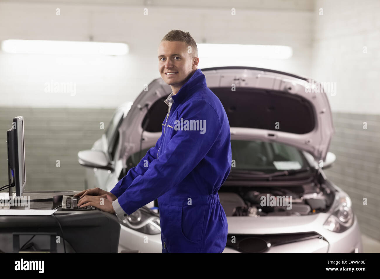 Smiling mechanic typing on a computer Stock Photo - Alamy