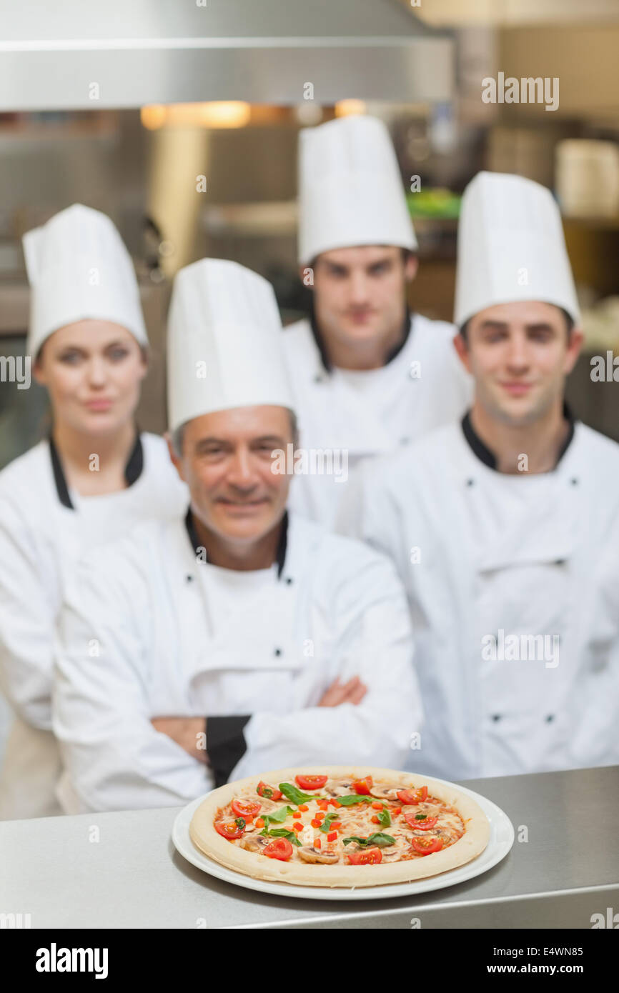 Pizza on the counter with team of Chef's behind Stock Photo - Alamy