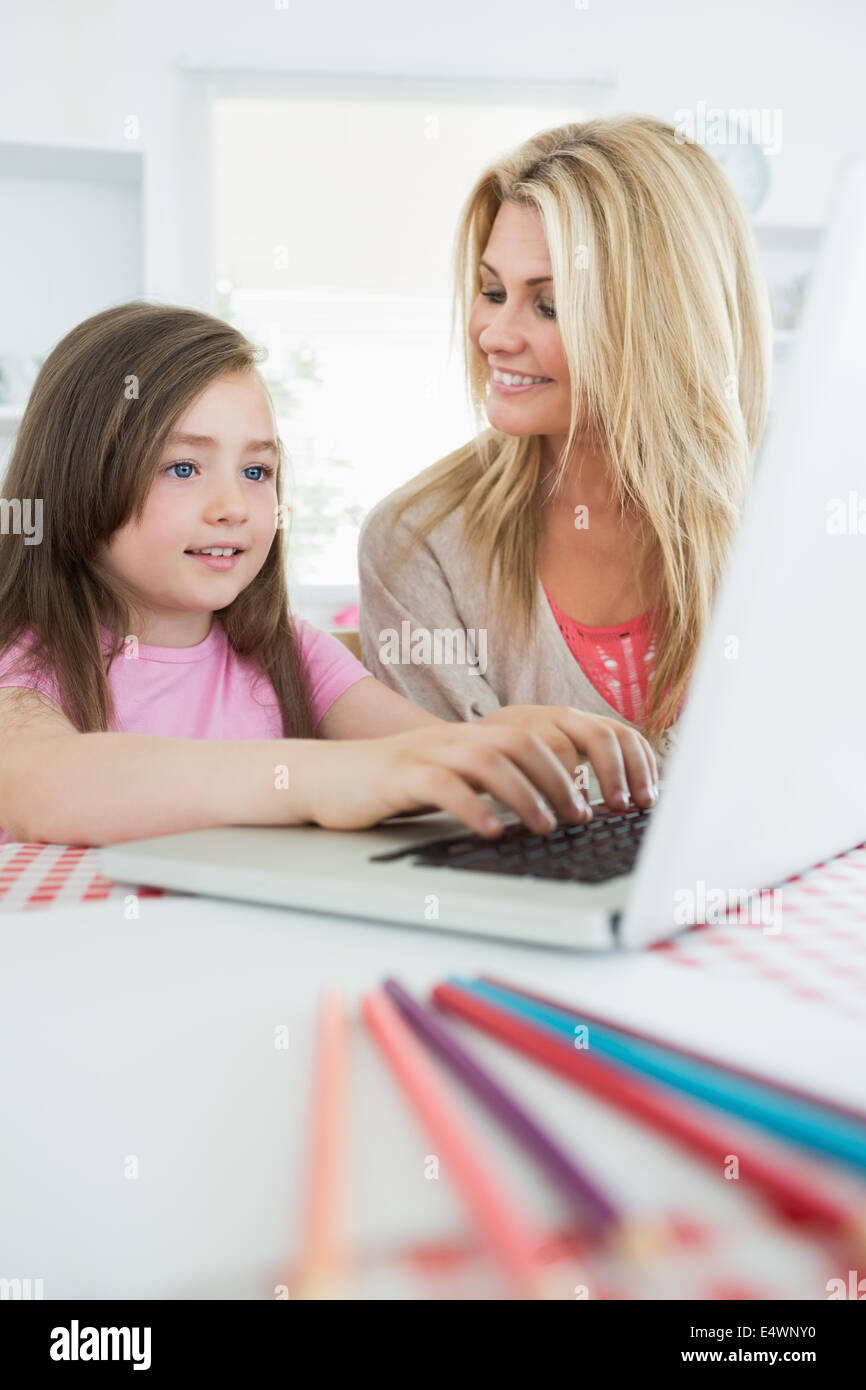 Little girl typing with mother smiling Stock Photo - Alamy