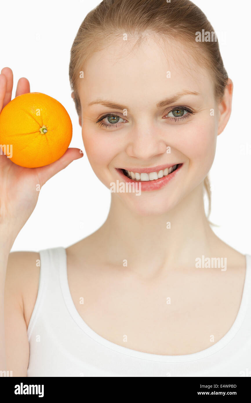 Smiling blonde-haired presenting an orange Stock Photo - Alamy
