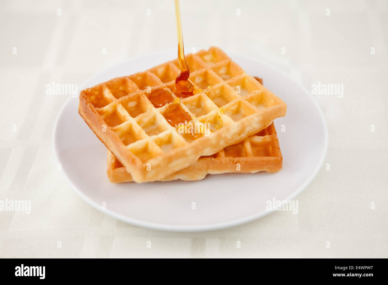 Honey falling on a waffle Stock Photo - Alamy