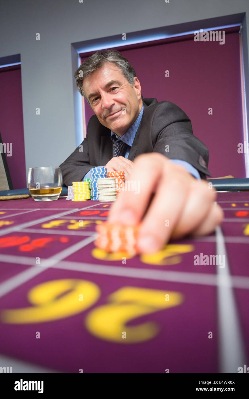 Man sitting and smiling while placing a bet Stock Photo - Alamy