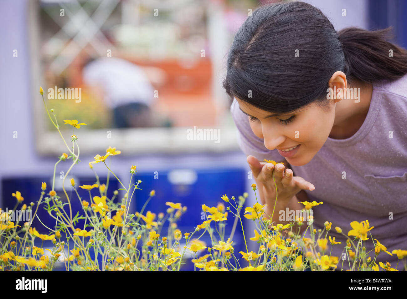 Woman smelling yellow flowers happily Stock Photo - Alamy