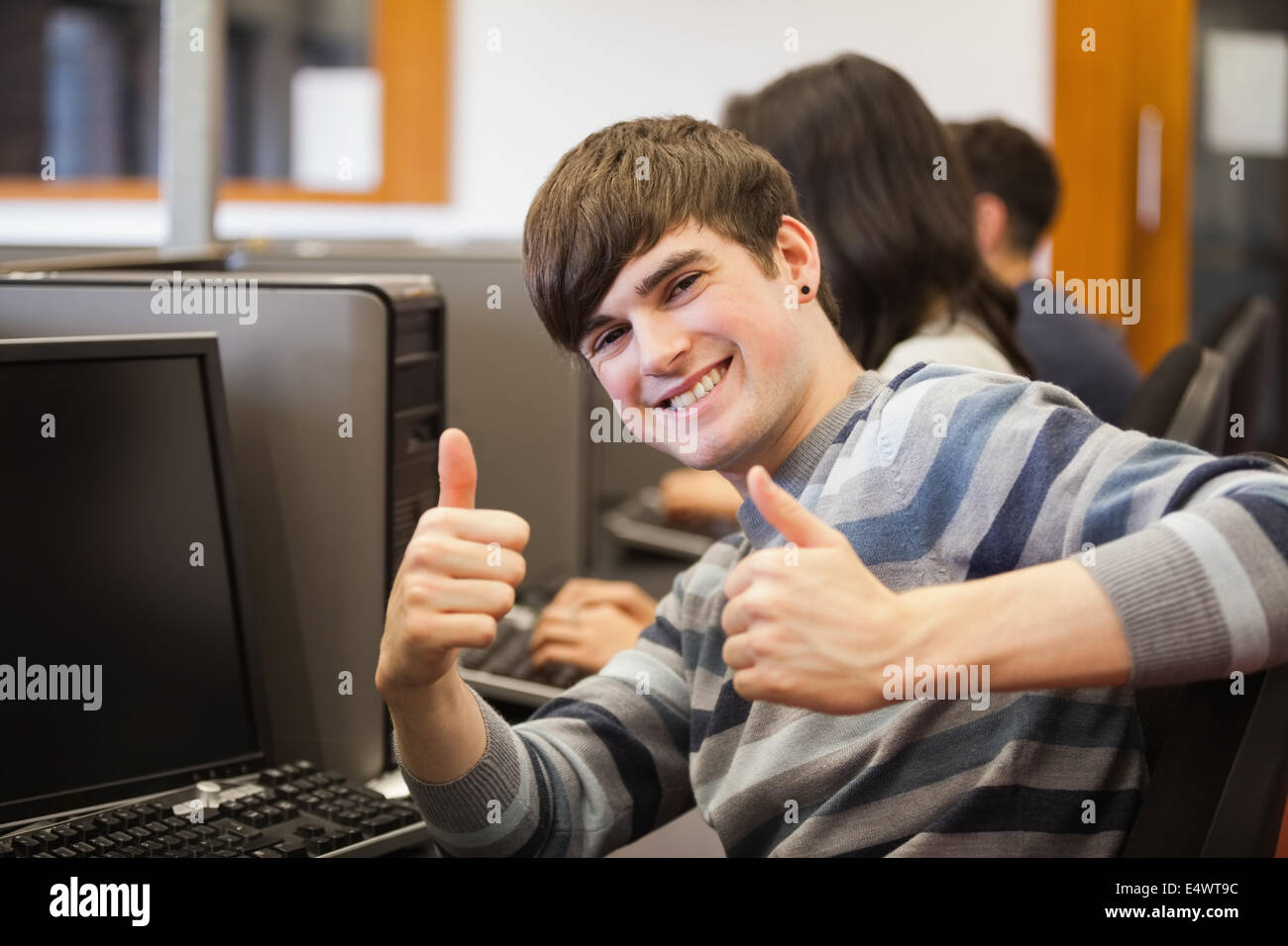 Man sitting at computer giving thumbs up Stock Photo - Alamy