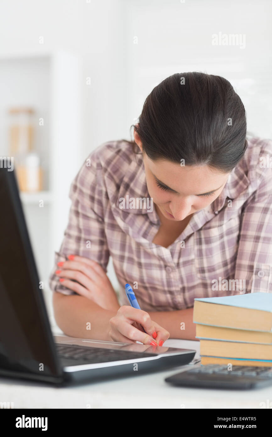 Woman writing on a notebook next to laptop Stock Photo - Alamy