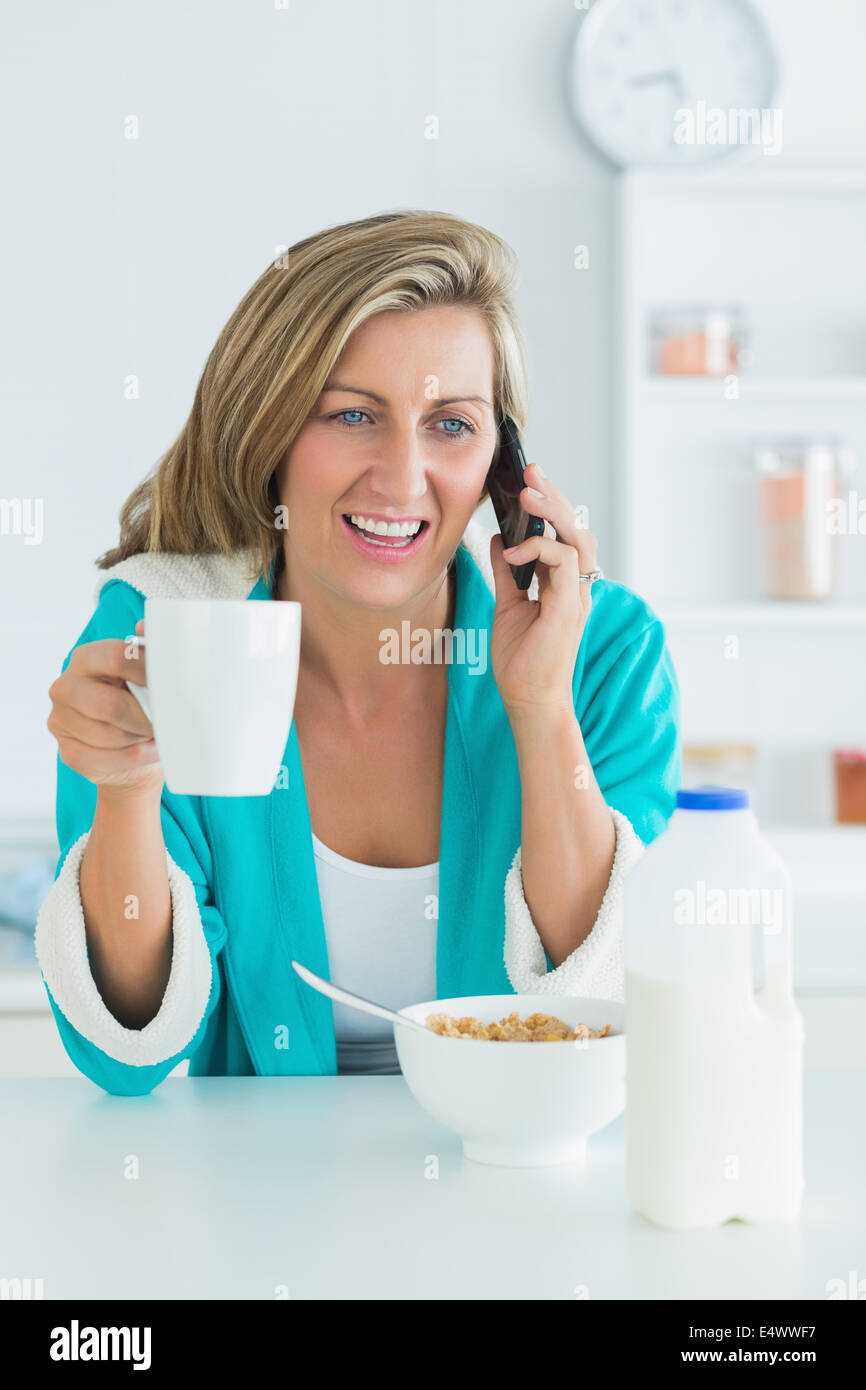 Smiling woman calling during her breakfast Stock Photo - Alamy