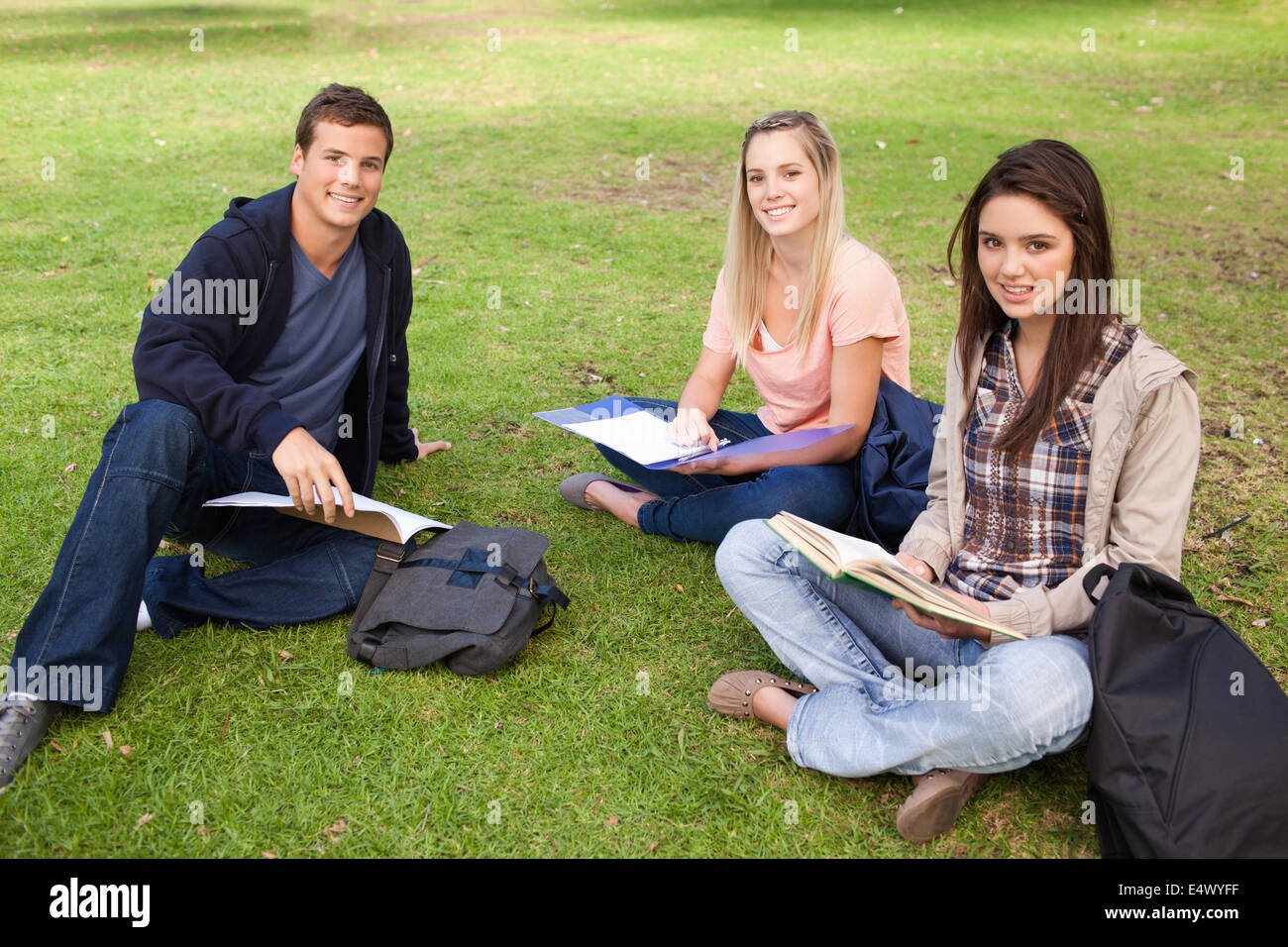 Three smiling students studying together Stock Photo - Alamy