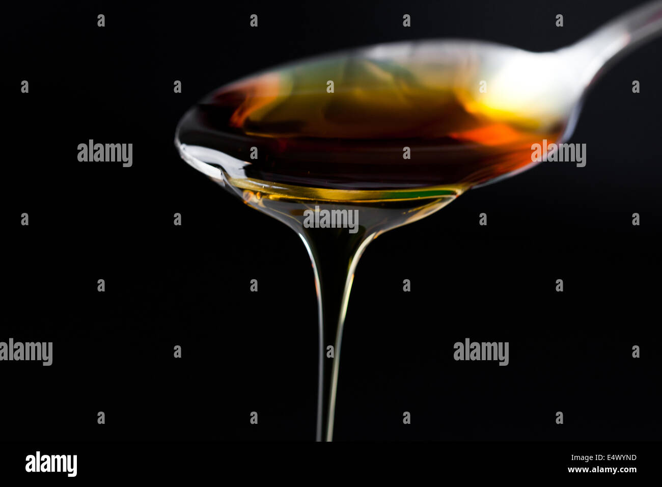 Honey trickle dropping of a full spoon Stock Photo - Alamy