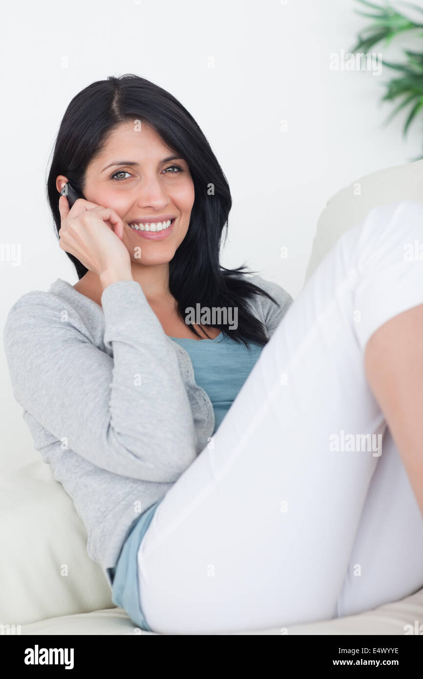 Woman telephoning while sitting on a couch Stock Photo - Alamy