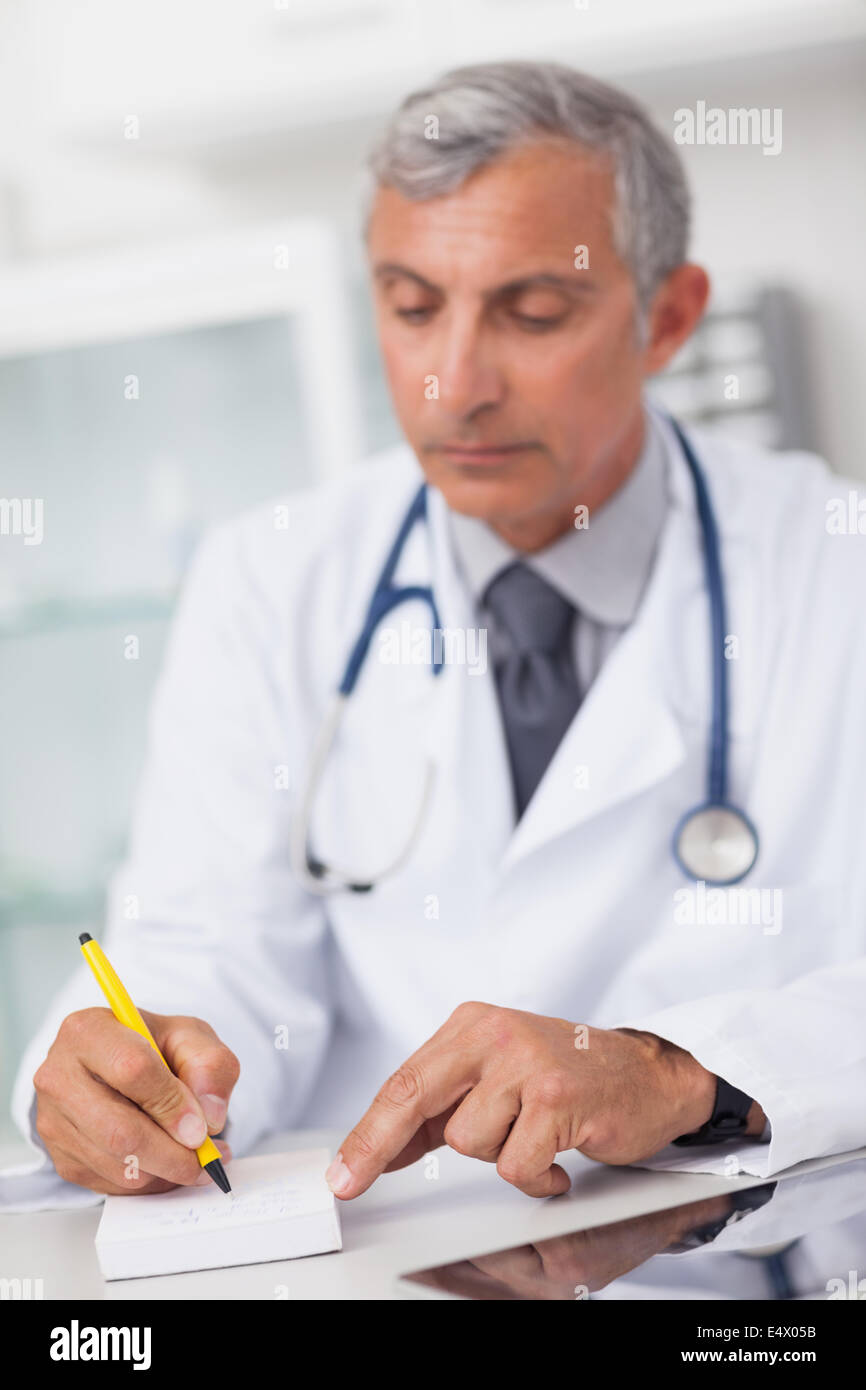 Doctor writing on a notepad at his desk Stock Photo - Alamy