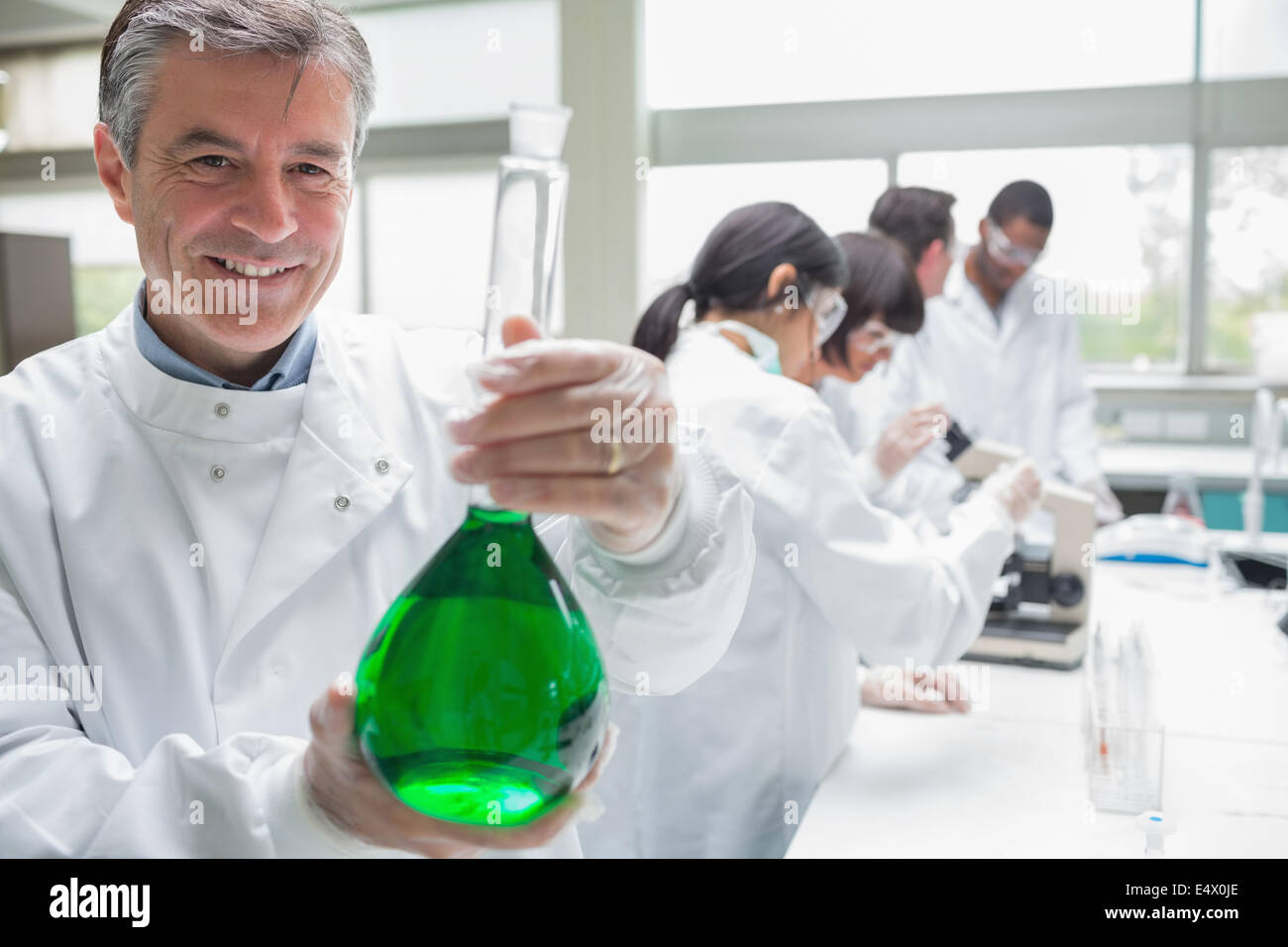Chemist smiling and holding beaker Stock Photo - Alamy