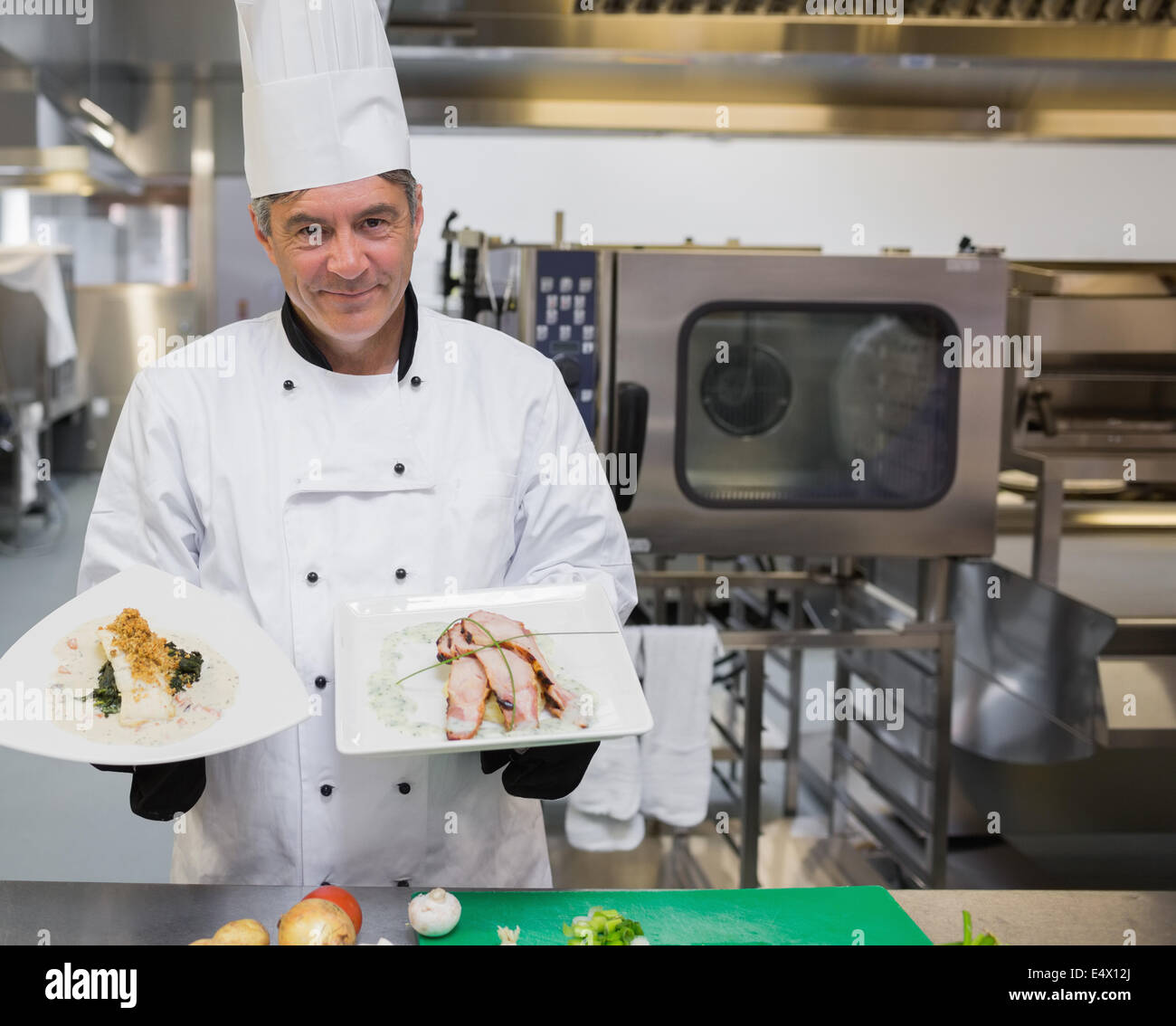 Chef holding two plates in the kitchen Stock Photo - Alamy