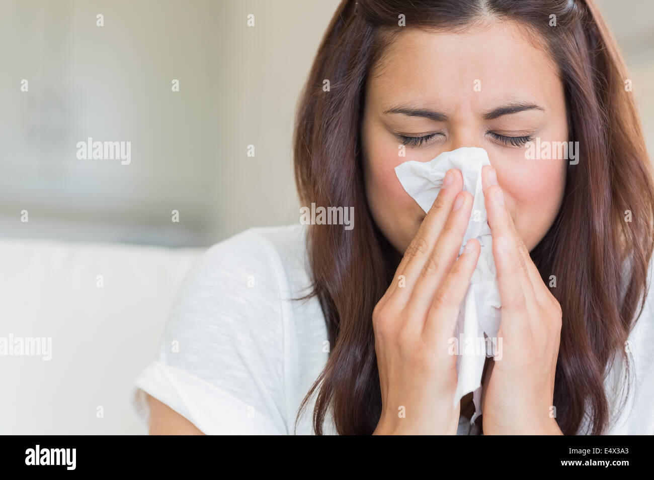 Brunette blowing nose into tissue Stock Photo - Alamy