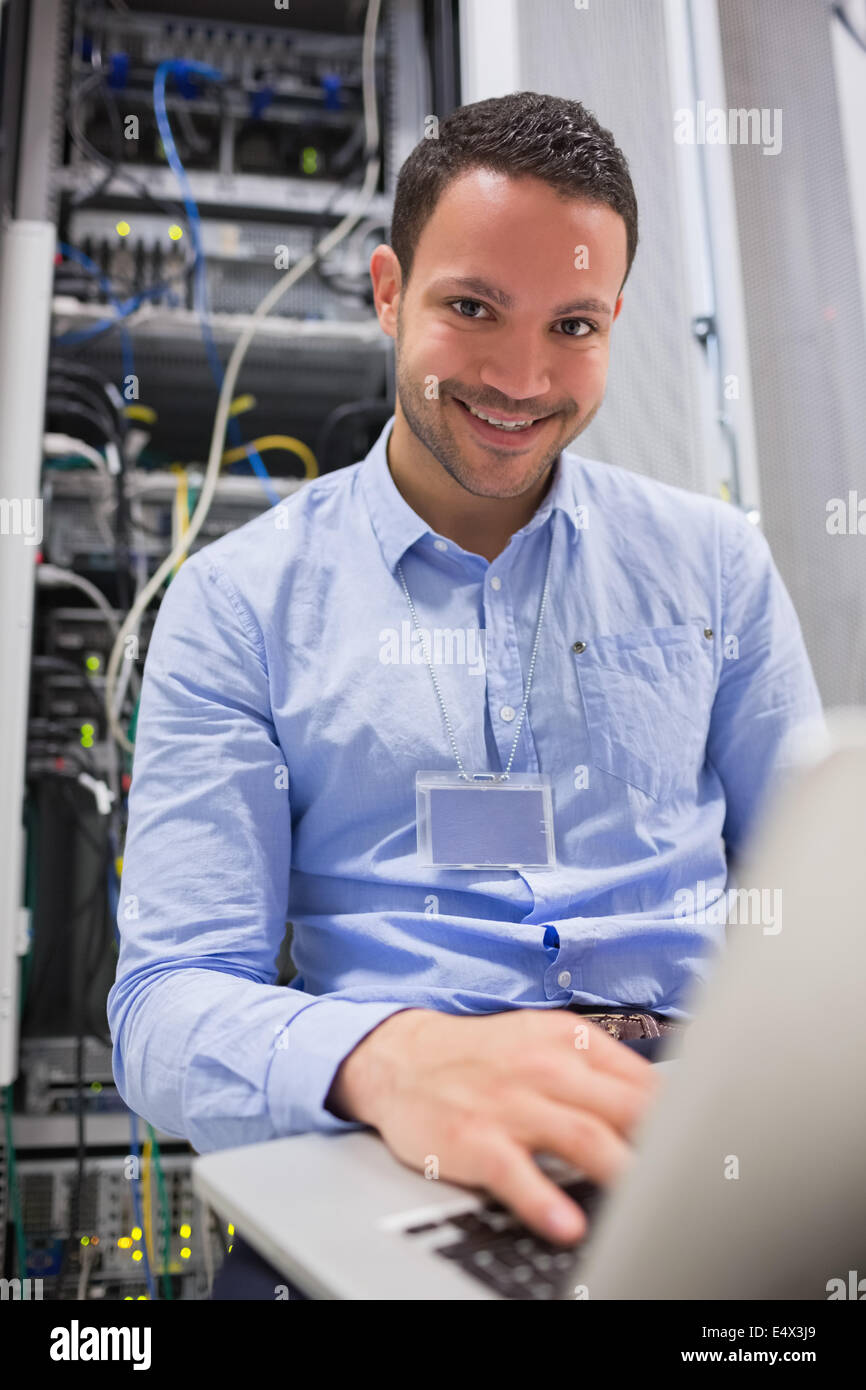 Smiling man working on servers with laptop Stock Photo - Alamy