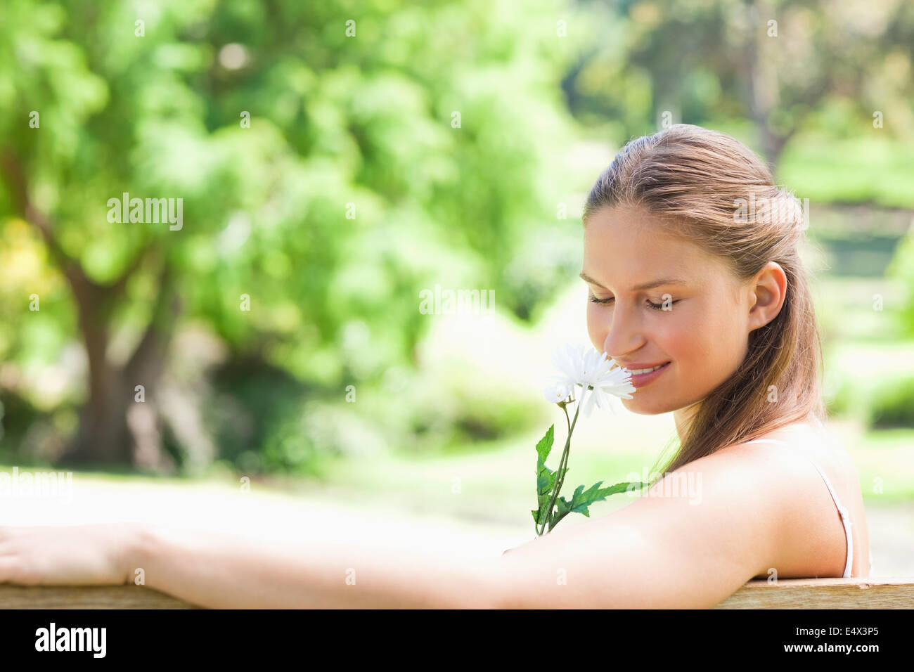 Side view of a woman smelling a flower Stock Photo - Alamy