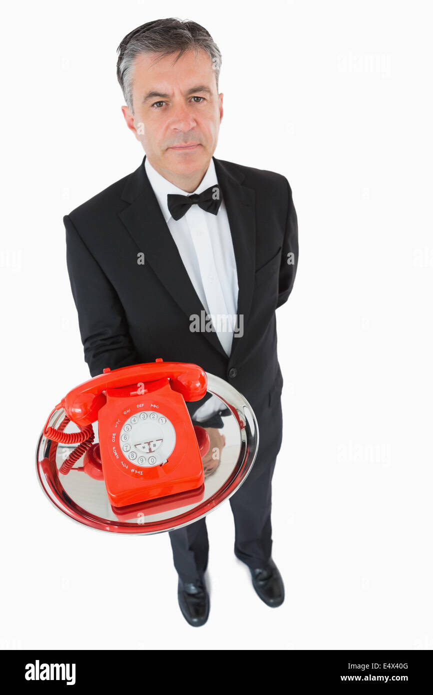 Waiter holding a red dial phone Stock Photo - Alamy