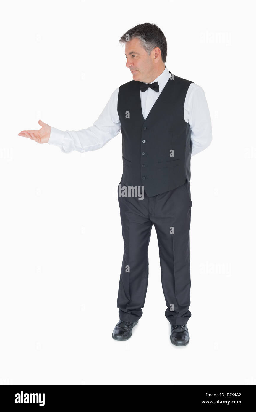 Waiter presenting something to the left Stock Photo - Alamy