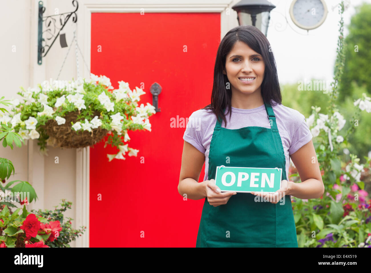 Florist holding open-sign in garden center Stock Photo - Alamy