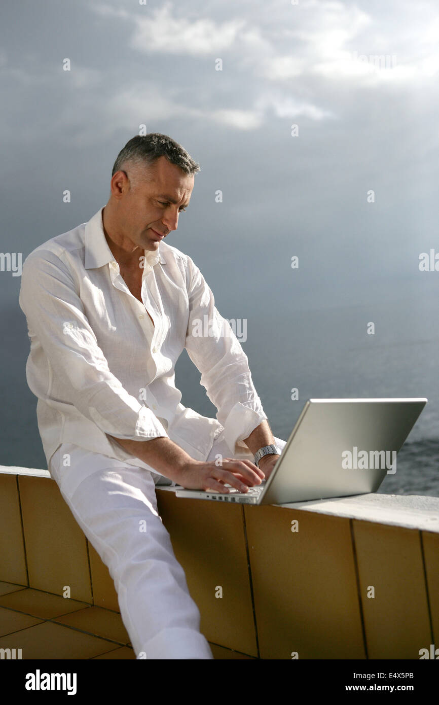 Man working on his laptop by the ocean Stock Photo - Alamy