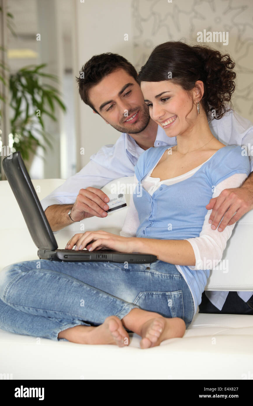 a couple doing computer on a couch Stock Photo - Alamy