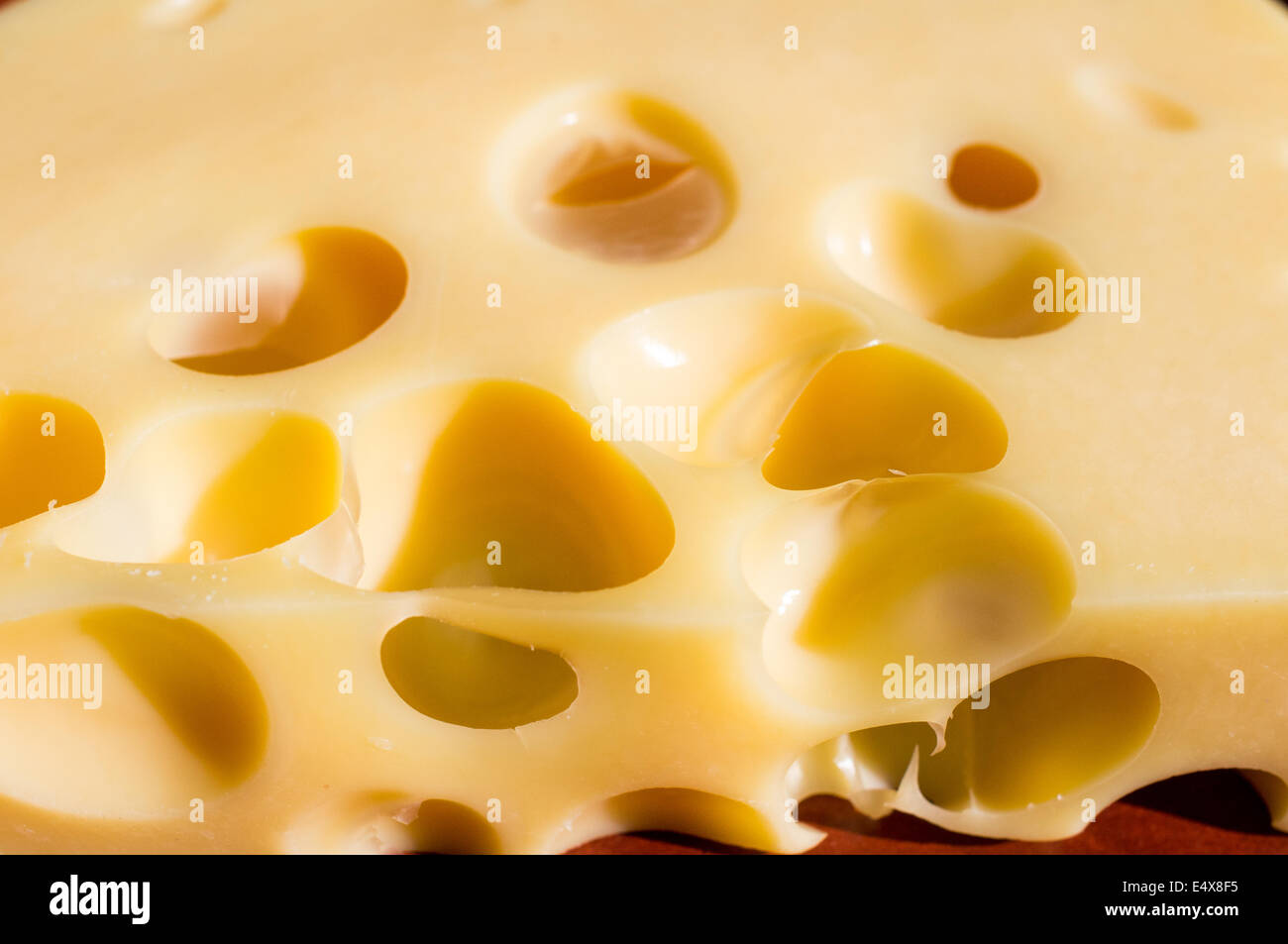 Piece of cheese with holes closeup Stock Photo - Alamy