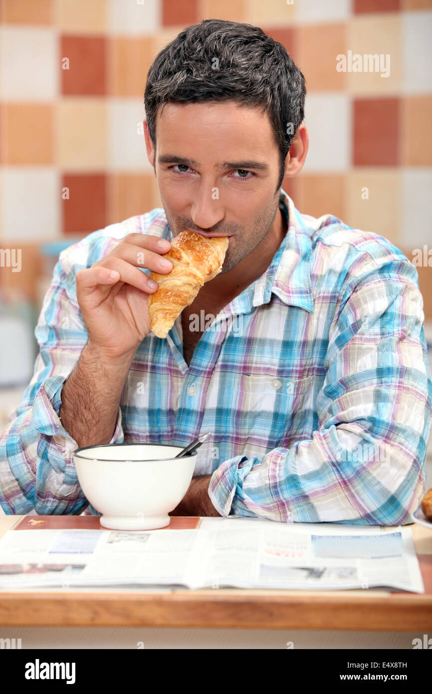 Handsome man eating a croissant Stock Photo - Alamy
