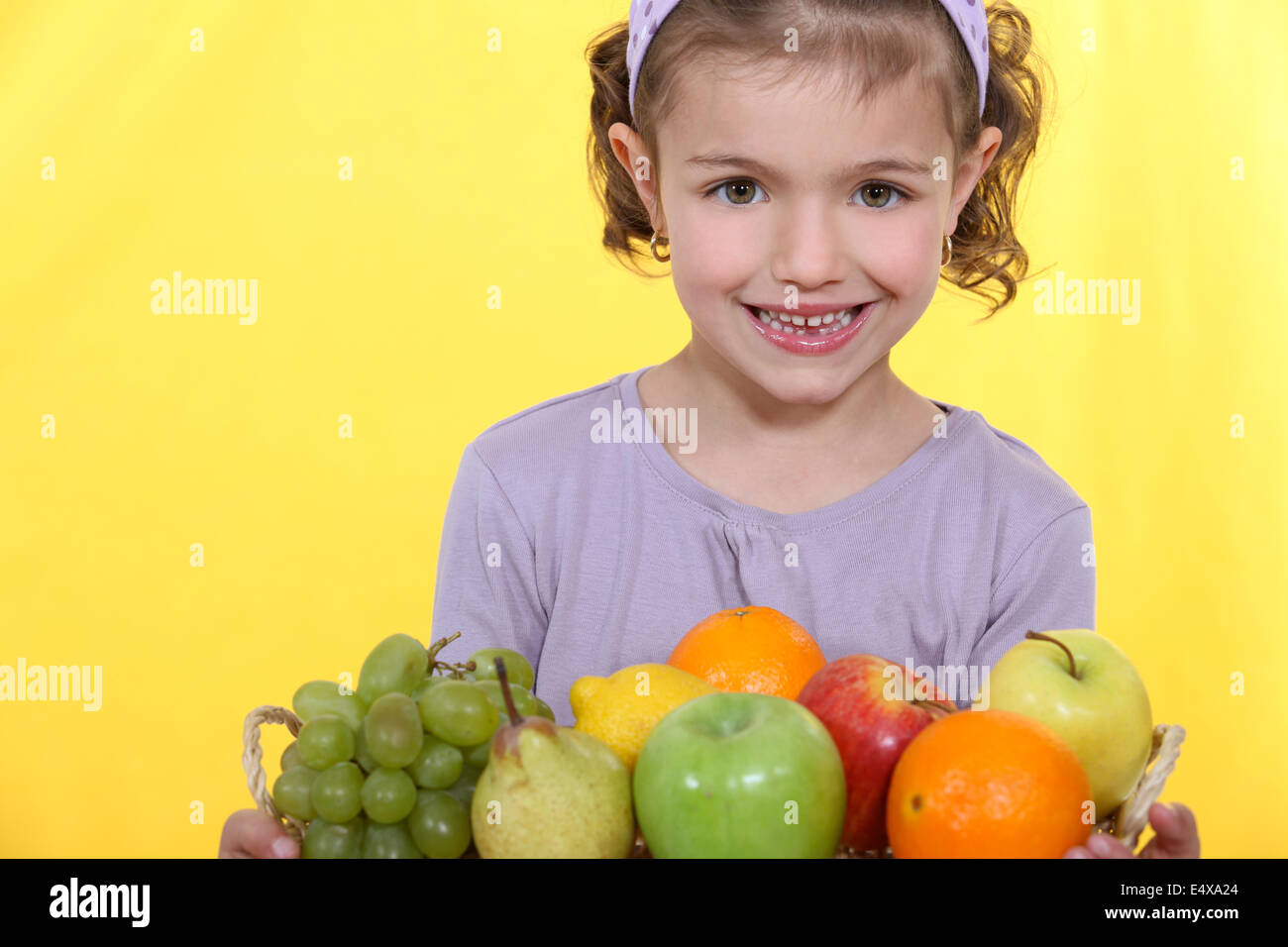 Little girl stood with fruit Stock Photo - Alamy