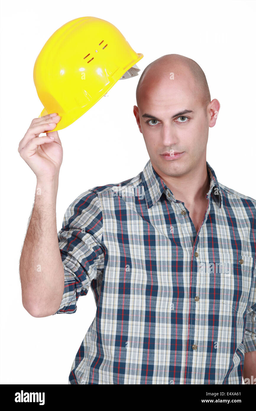 Bald young builder lifting hat Stock Photo - Alamy
