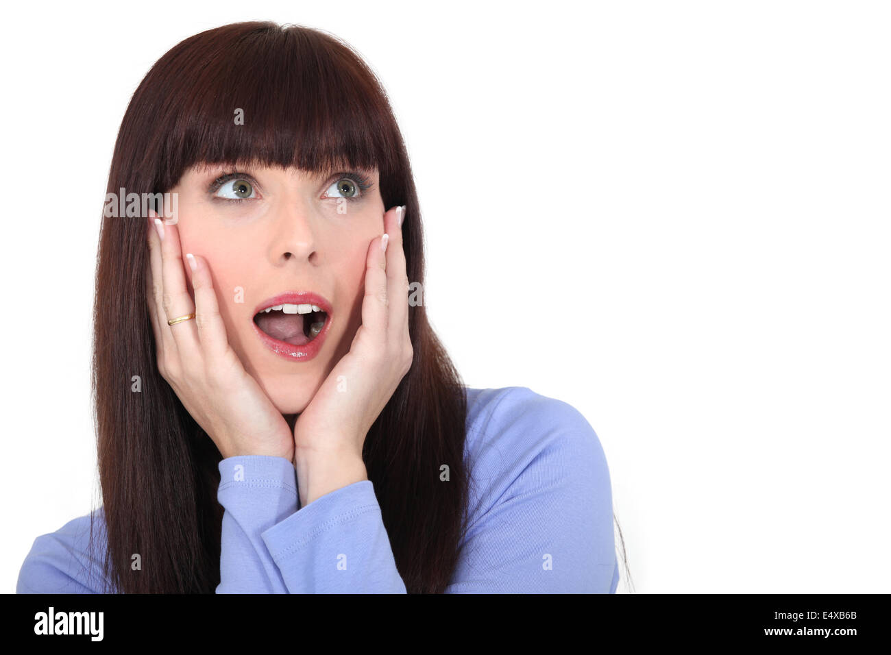 Shocked brunette holding hands to face Stock Photo - Alamy