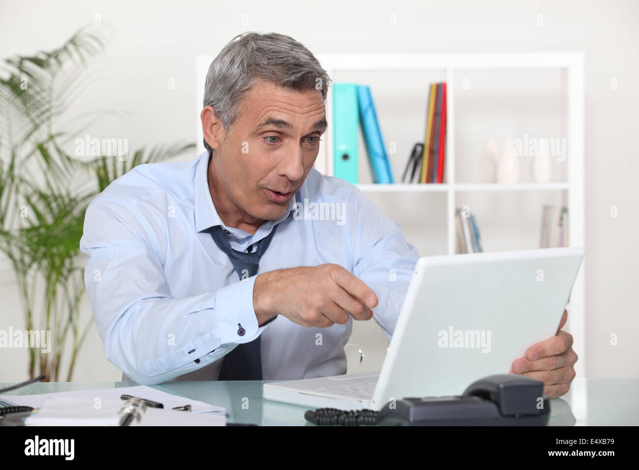 Businessman laughing in front of a laptop Stock Photo - Alamy