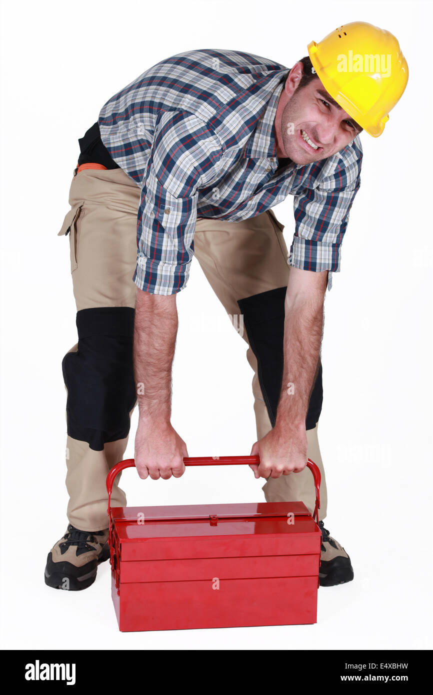 Builder struggling to lift heavy tool box Stock Photo - Alamy