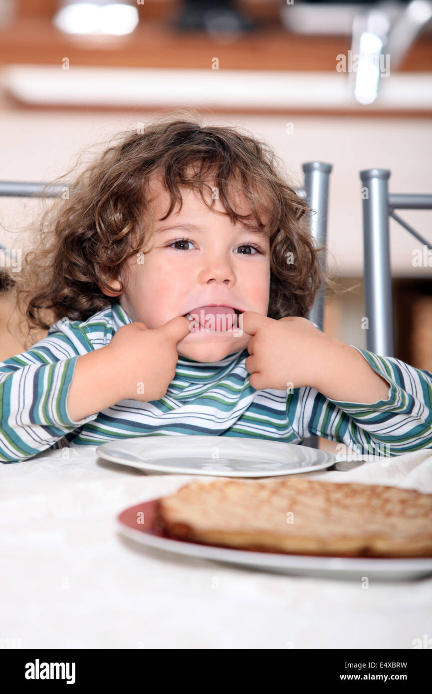 Toddler pulling a face at the table Stock Photo - Alamy
