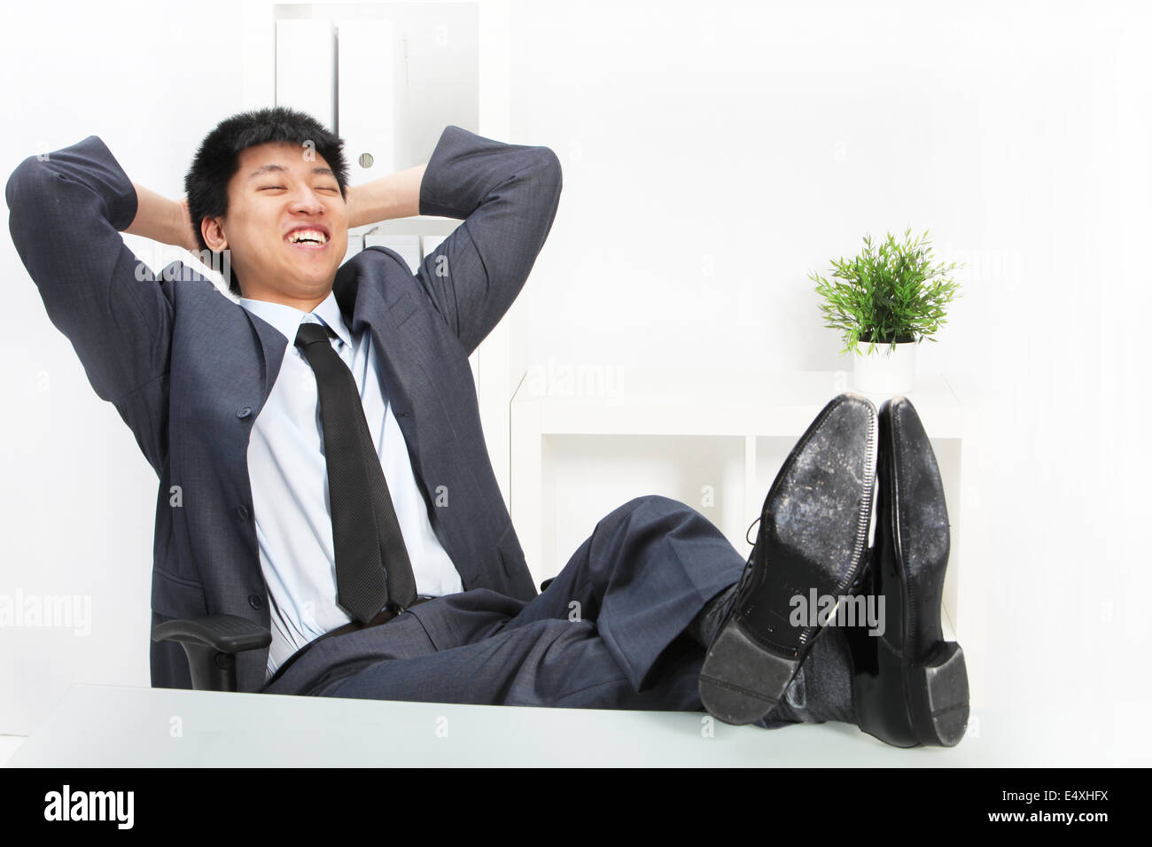 Asian businessman relaxing with his feet up Stock Photo - Alamy