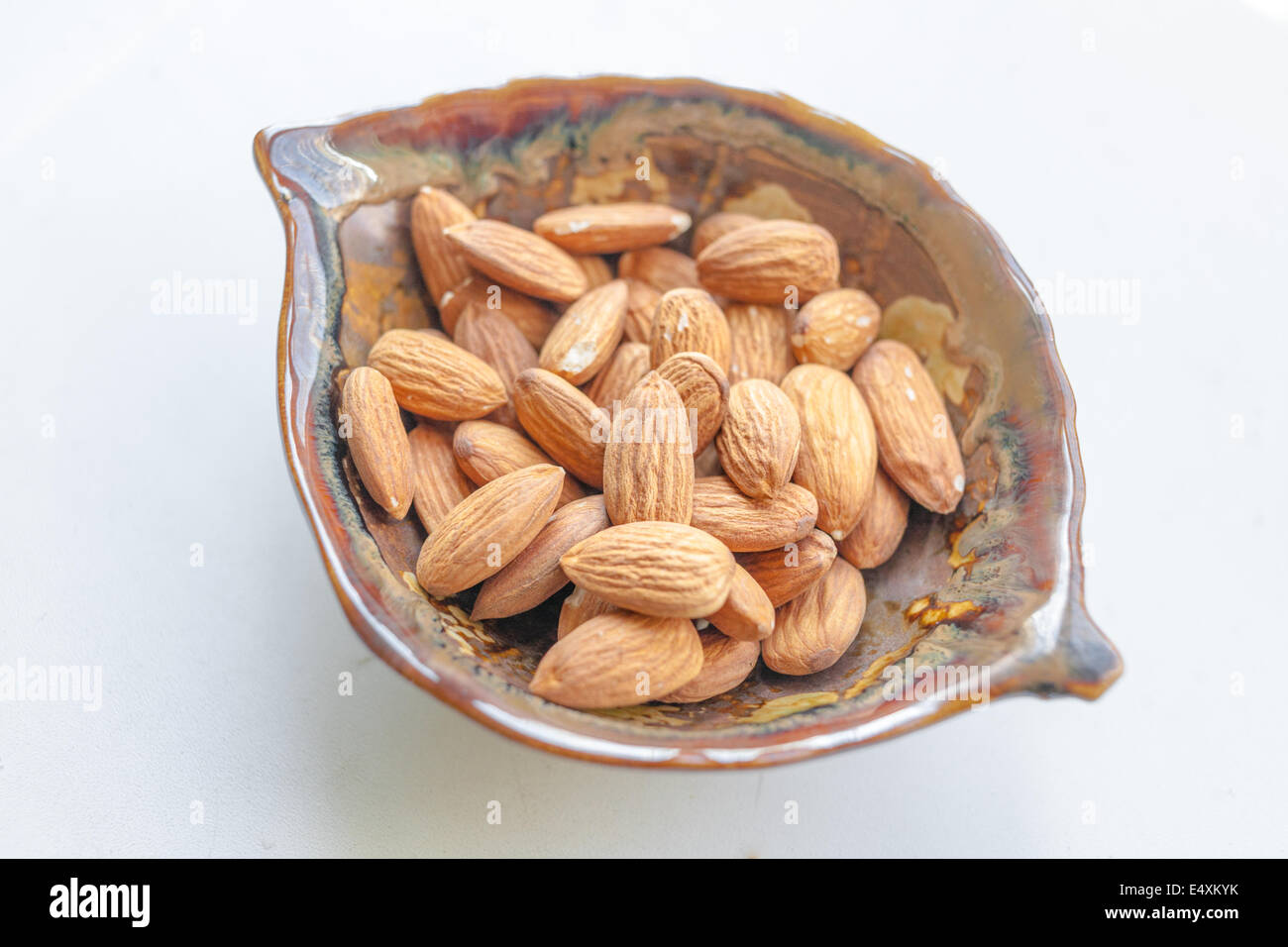 Bowl full of almonds on white with shadow Stock Photo - Alamy