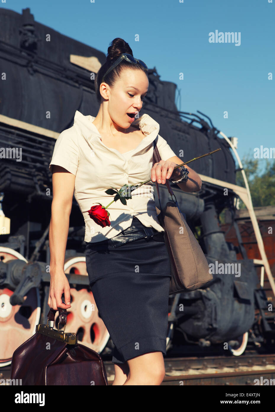 Woman with a suitcase looks at her clock Stock Photo - Alamy