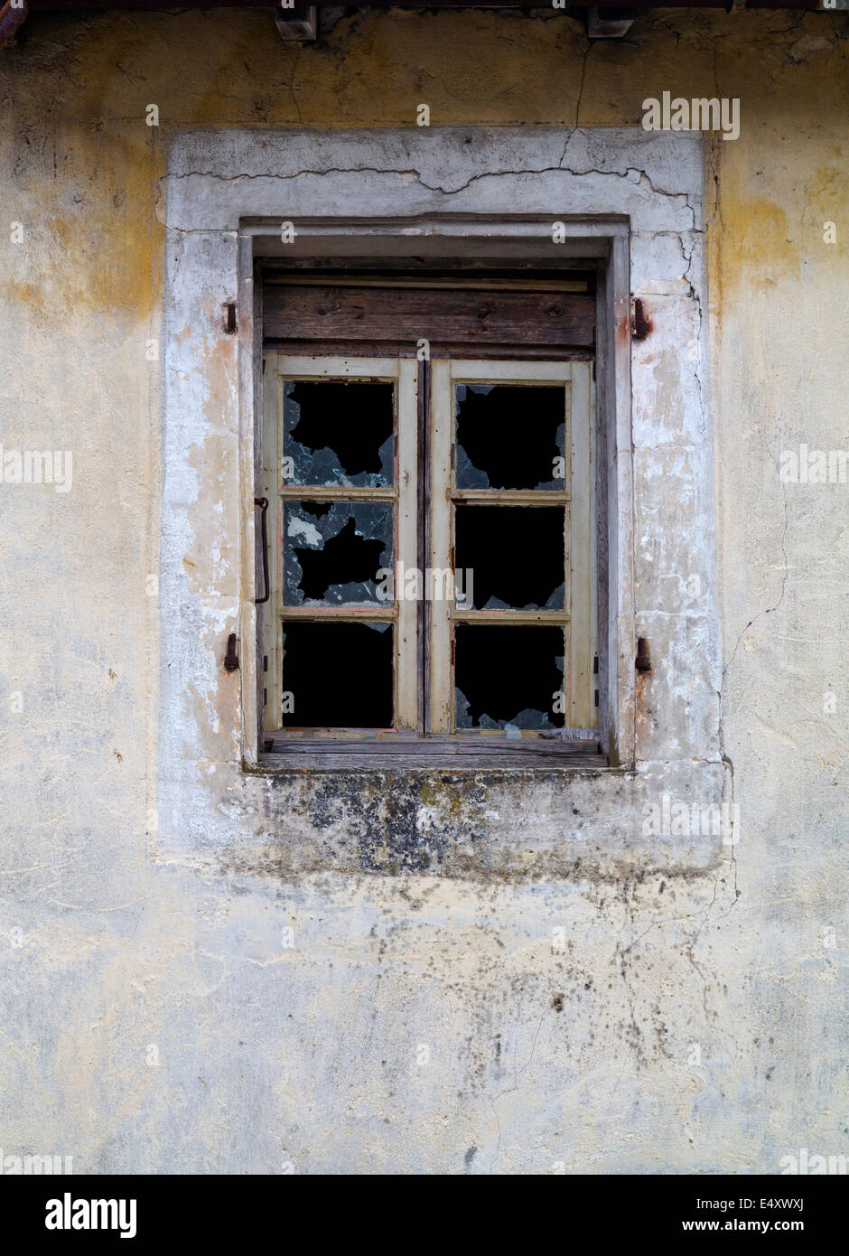 Broken glass in a window with wooden frames with decaying plaster on ...
