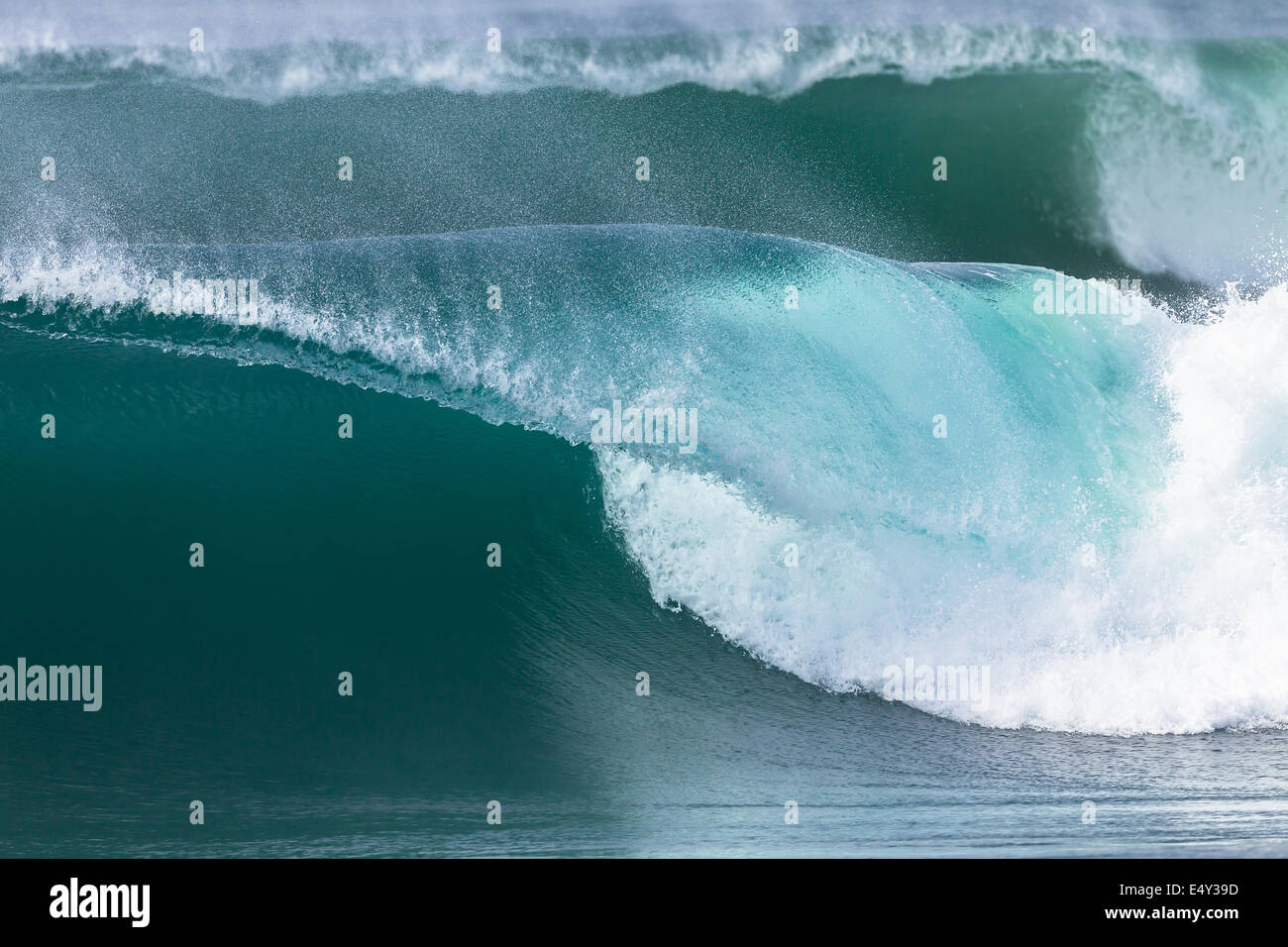 Blue clean ocean wave shape with hollow curling lip onto shallow beach ...