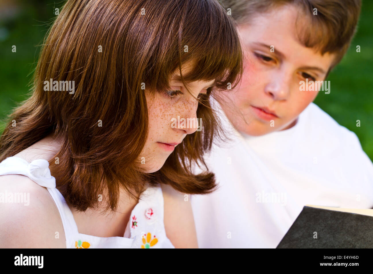 Portrait of cute kids reading books in natural environment Stock Photo ...