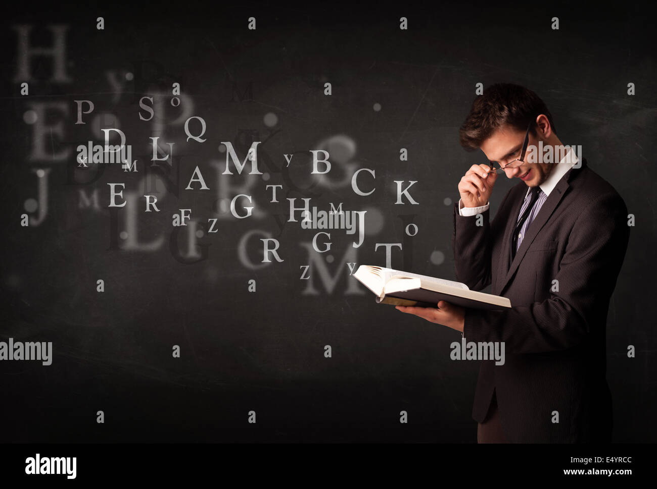 Young man reading a book with alphabet letters Stock Photo - Alamy