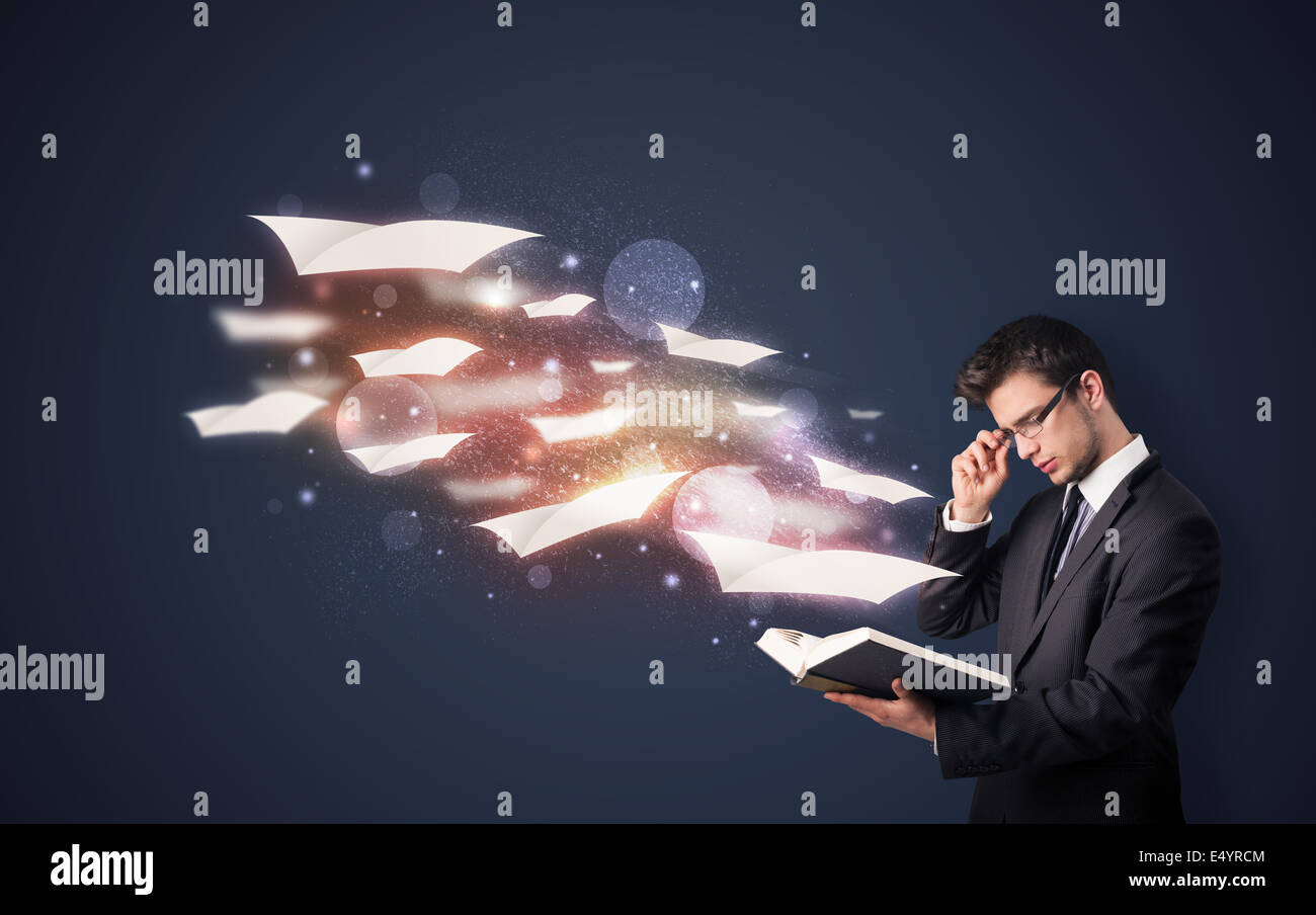 Young guy reading a book with flying sheets coming out of the book ...