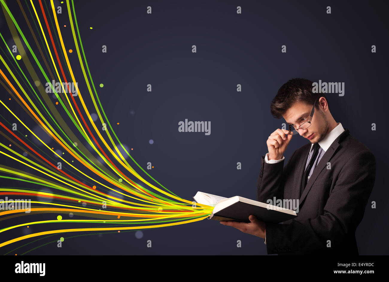 Handsome man reading a book while colorful lines are coming out of the ...