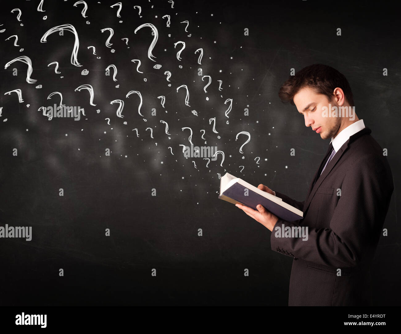 Young man reading a book with question marks coming out from it Stock ...