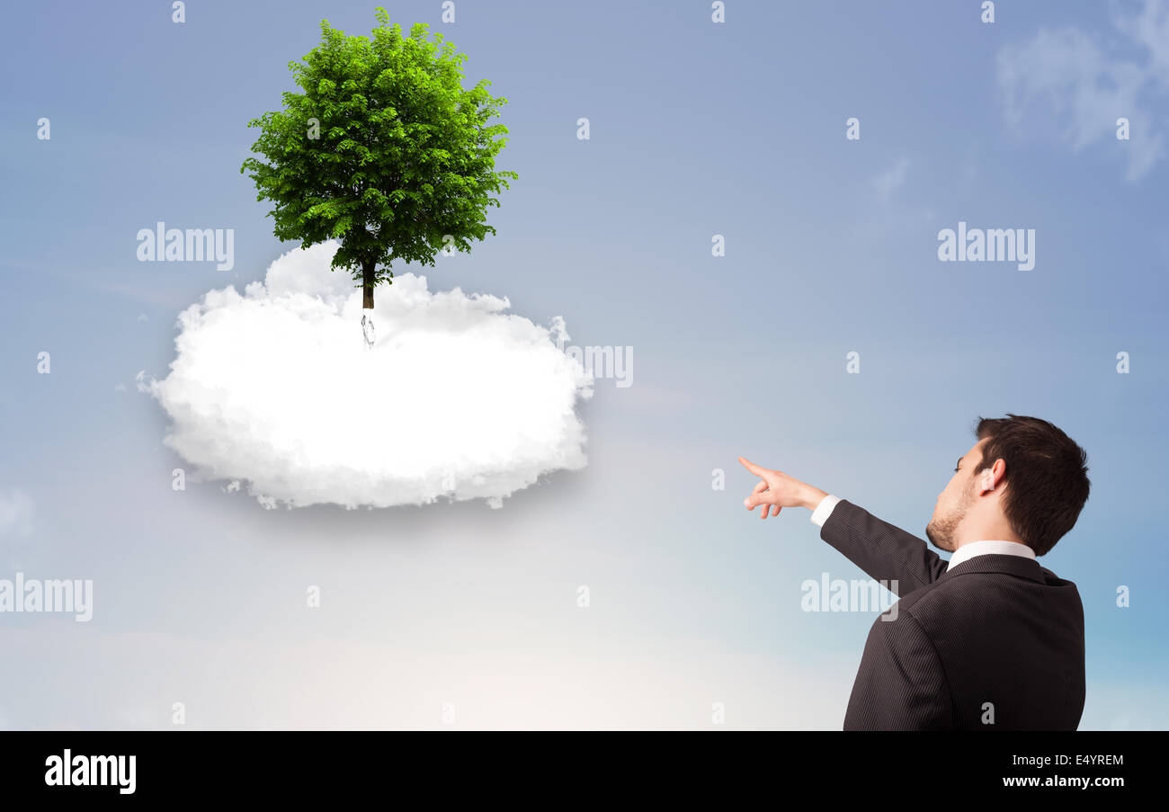 Young man pointing at a green tree on top of a white cloud Stock Photo ...