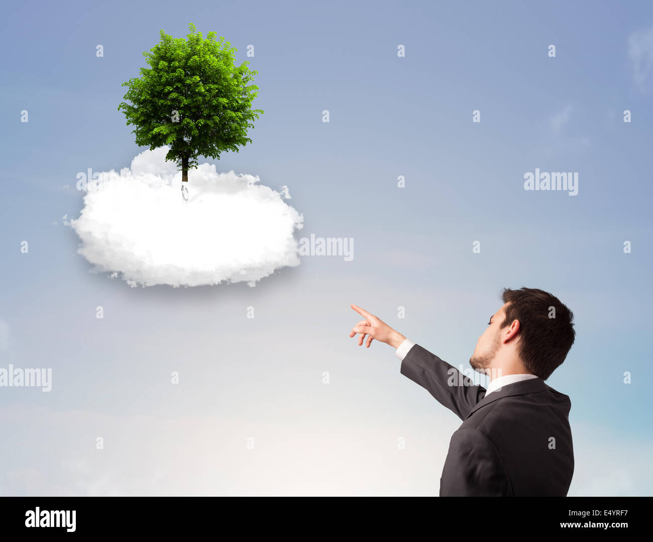 Young man pointing at a green tree on top of a white cloud Stock Photo ...