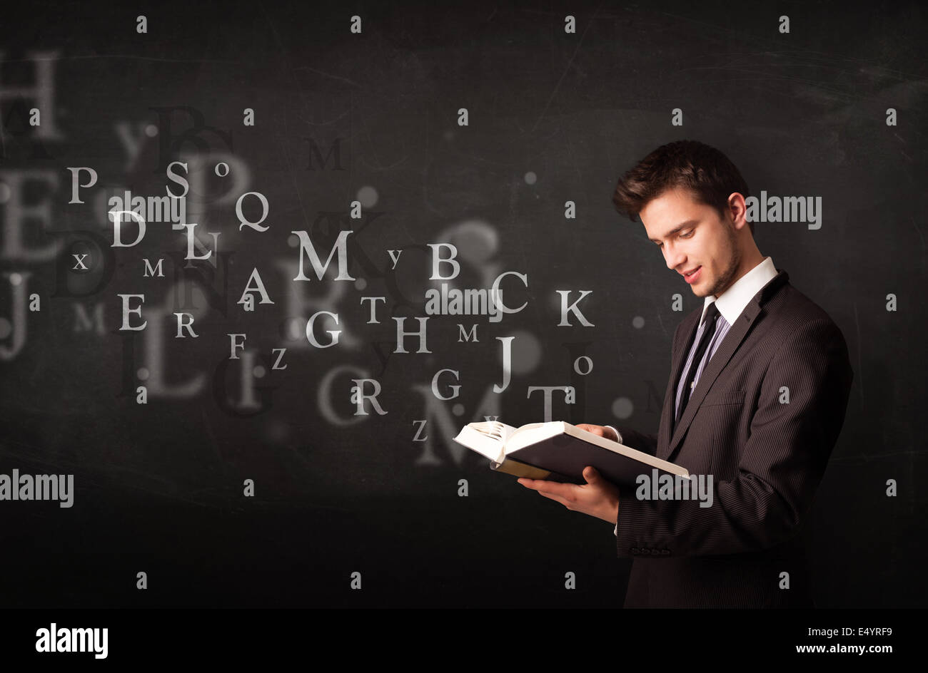 Young man reading a book with alphabet letters Stock Photo - Alamy