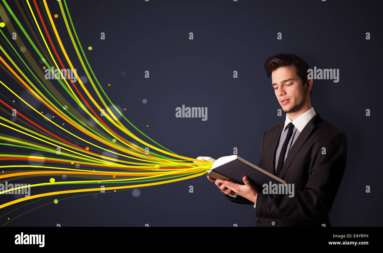 Handsome man reading a book while colorful lines are coming out of the ...