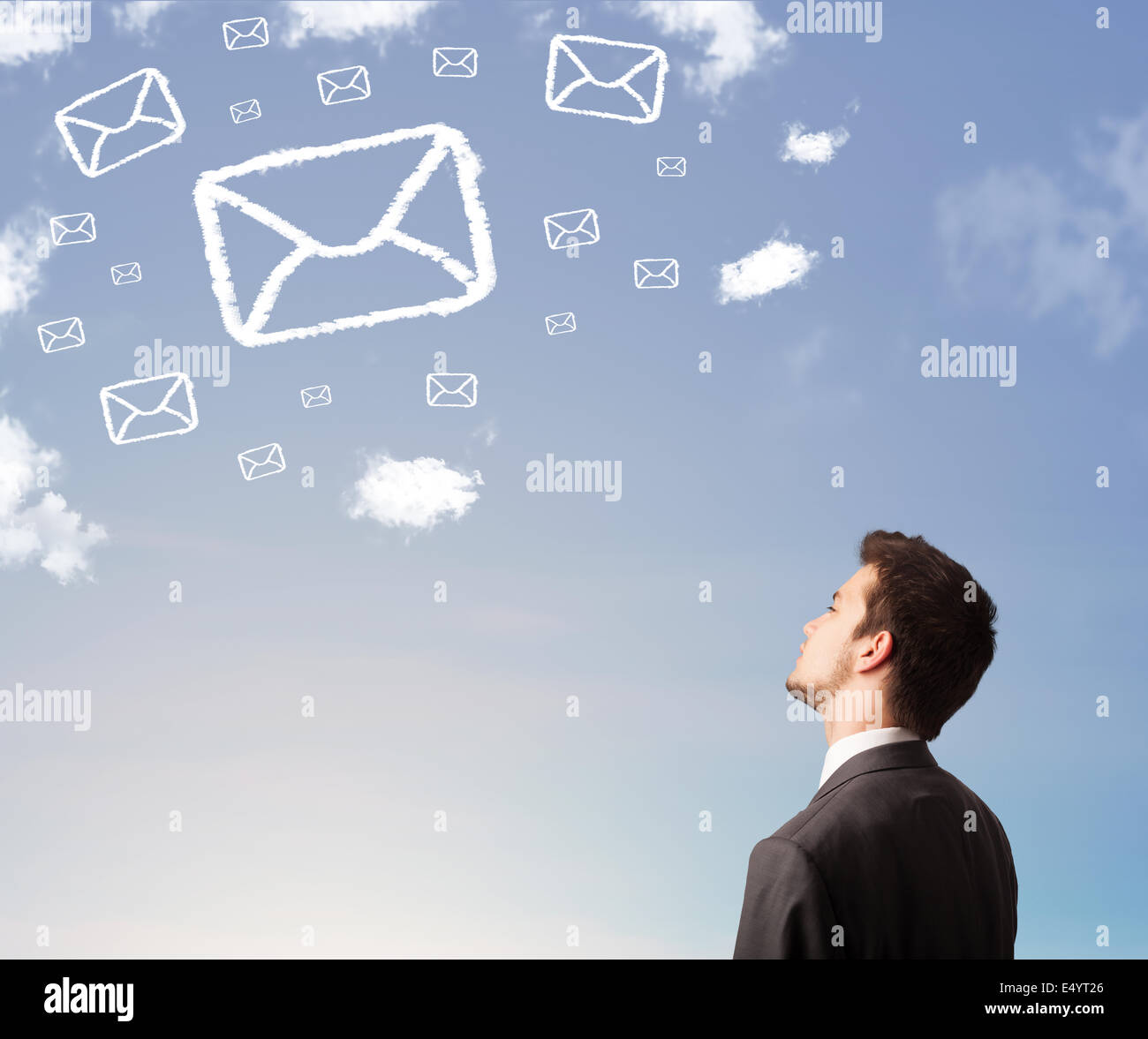 Businessman looking at mail symbol clouds on blue sky Stock Photo - Alamy