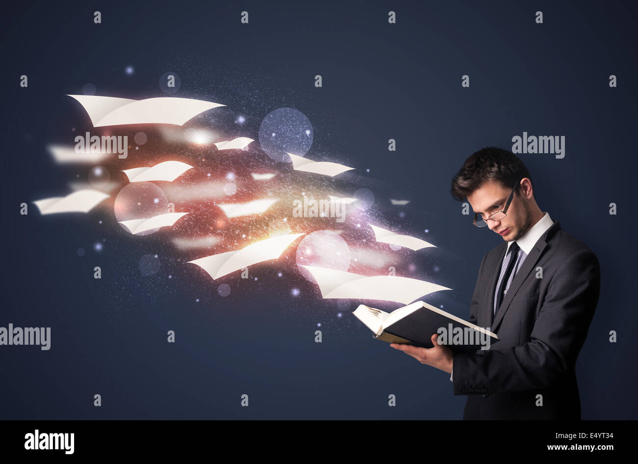 Young guy reading a book with flying sheets coming out of the book ...