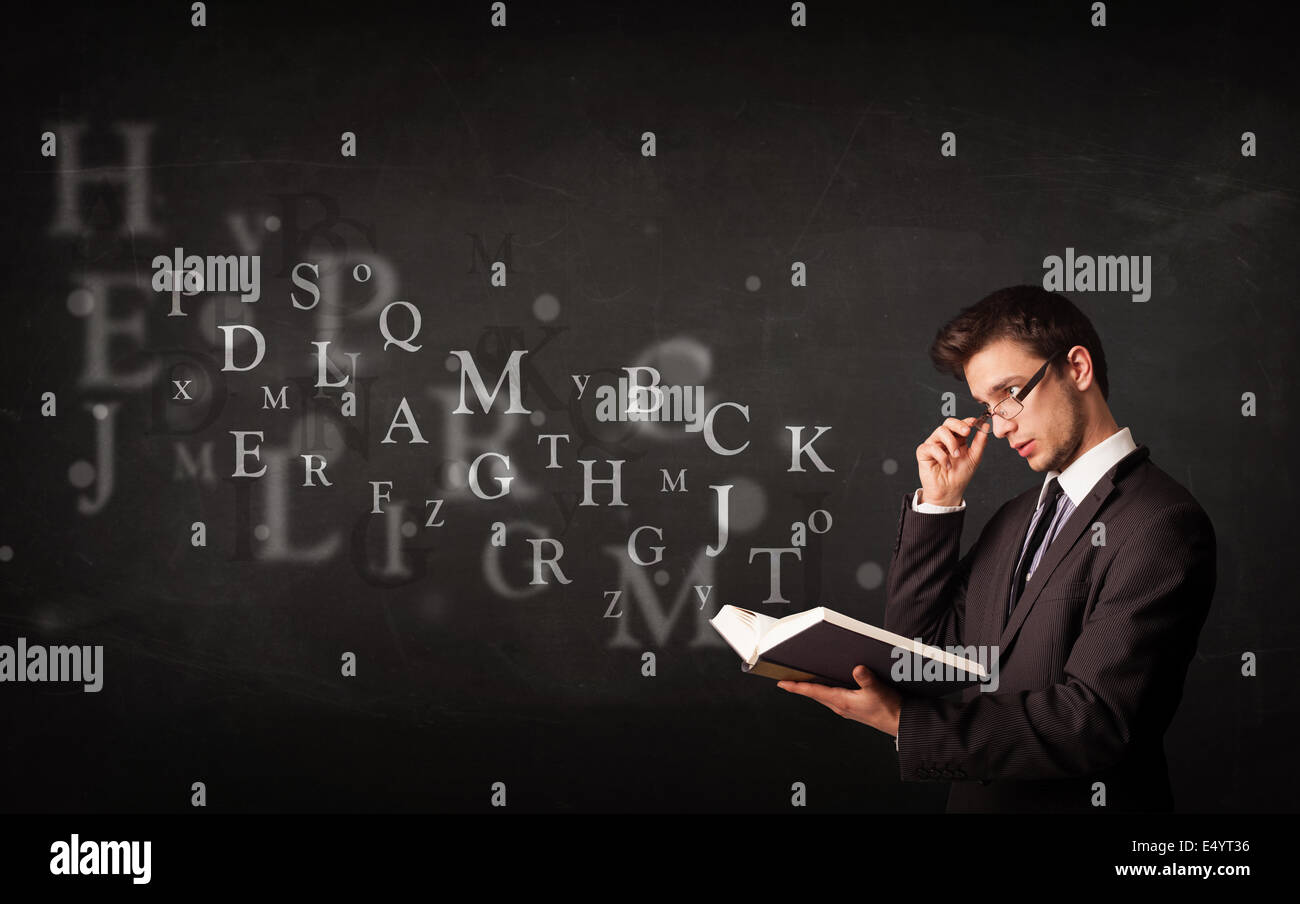 Young man reading a book with alphabet letters Stock Photo - Alamy