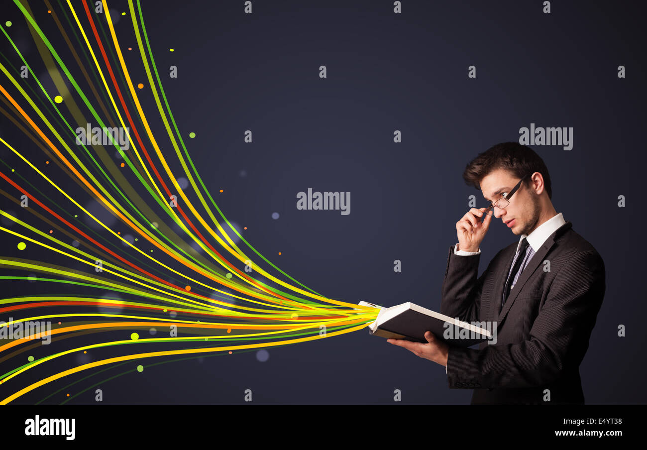 Handsome man reading a book while colorful lines are coming out of the ...